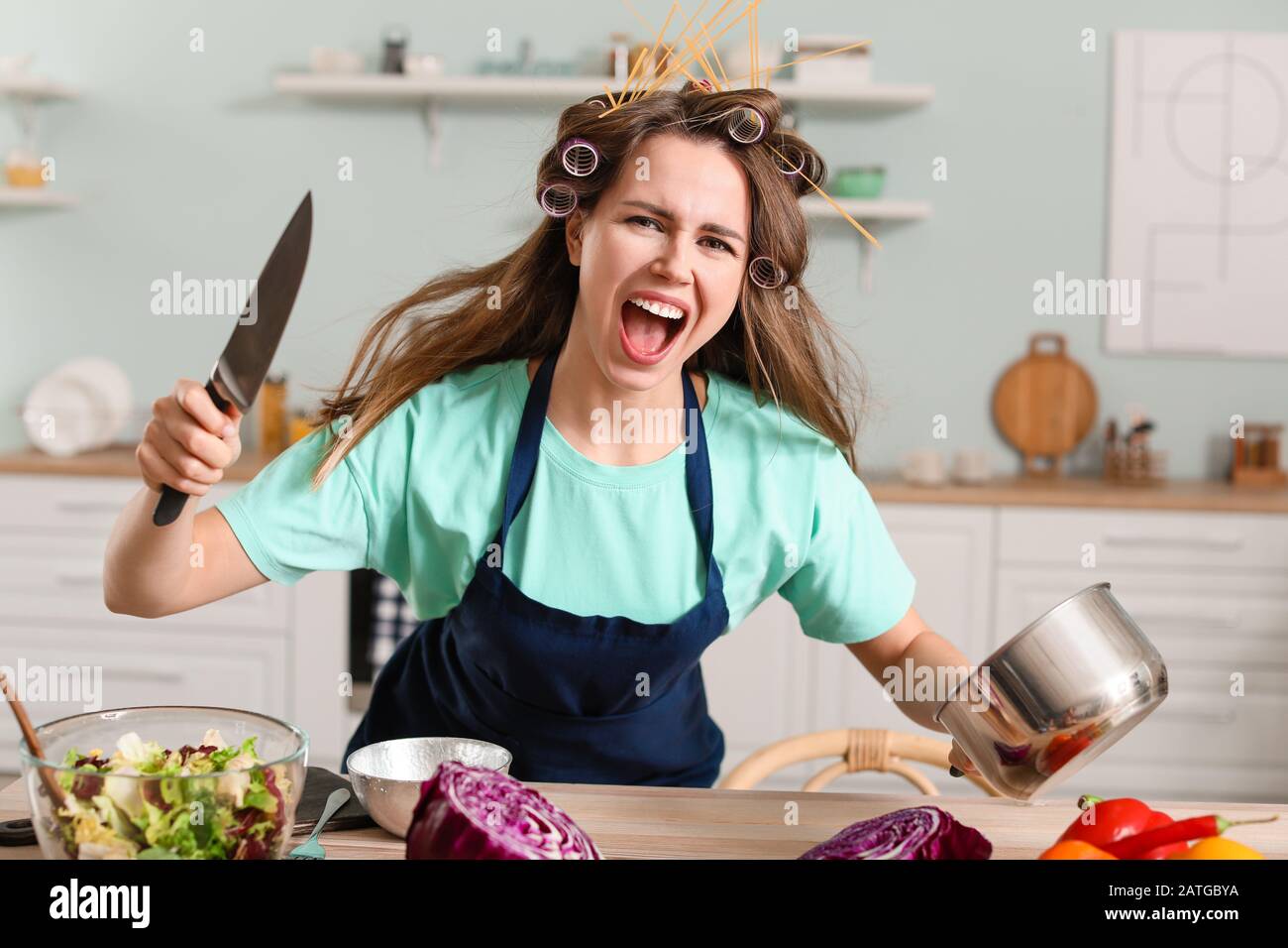 Aggressive young housewife cooking in kitchen Stock Photo - Alamy