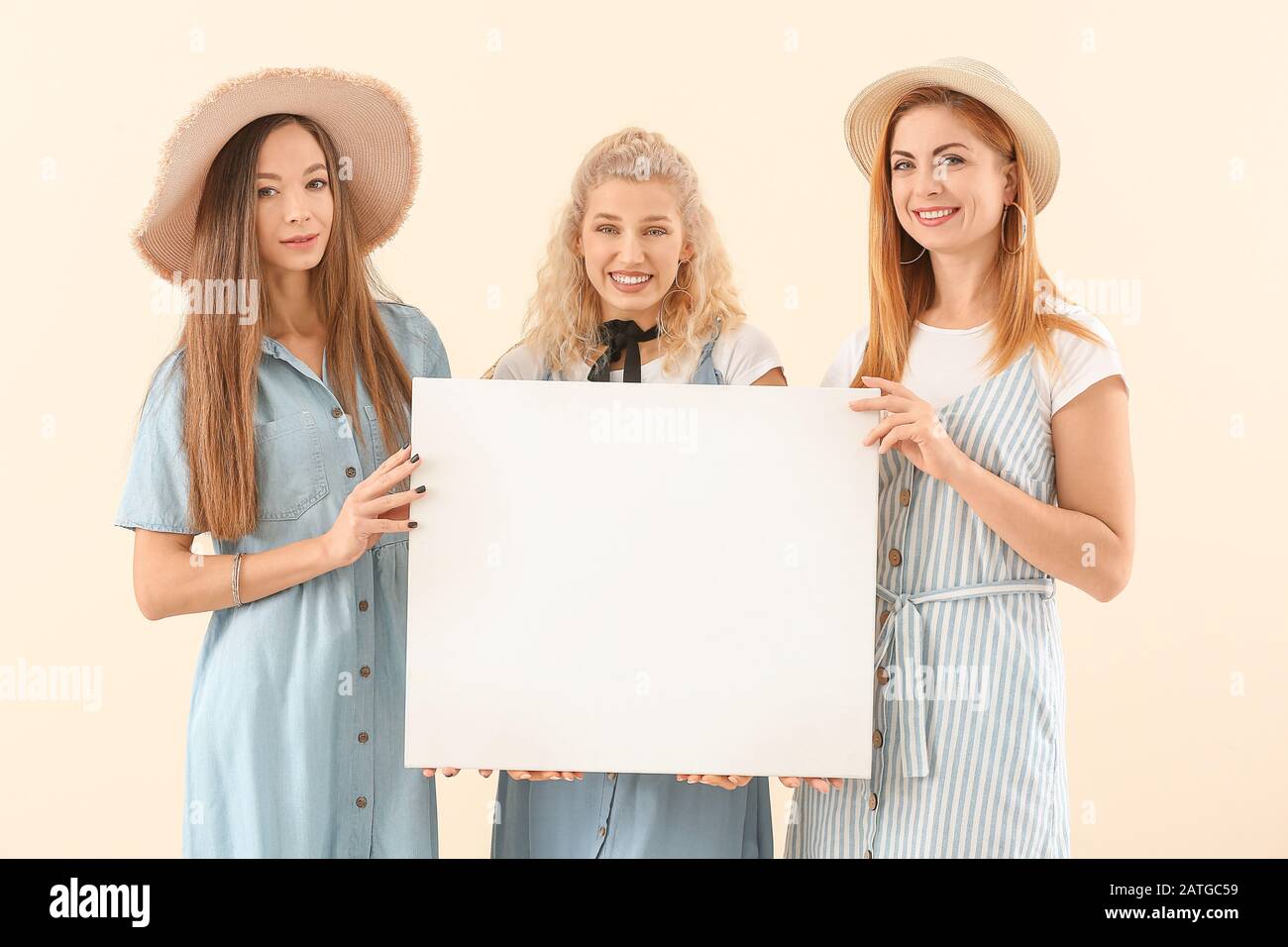 Beautiful young women with blank poster on color background Stock Photo ...