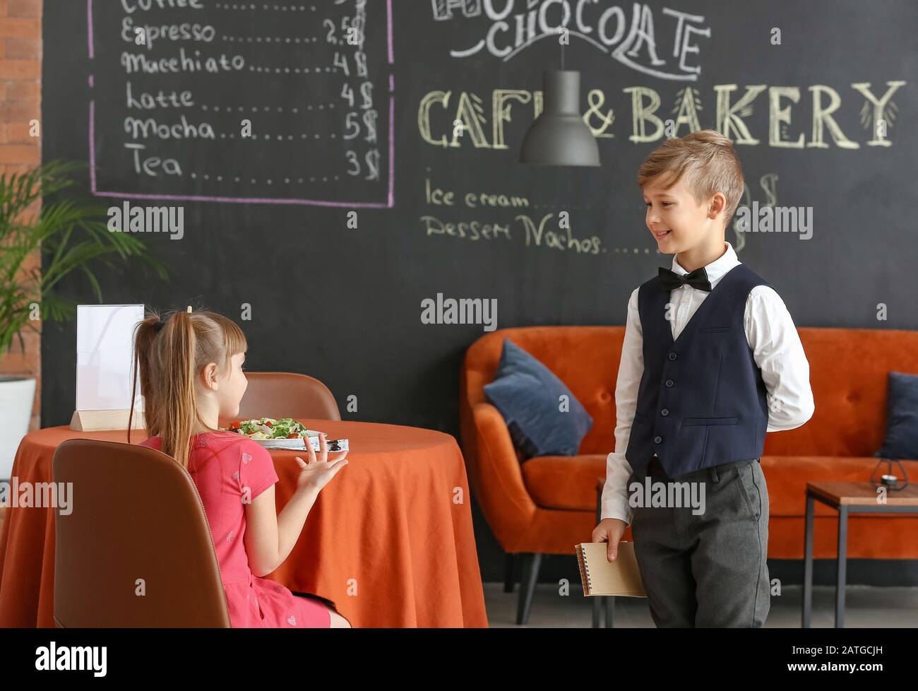 Cute little waiter serving client in restaurant Stock Photo - Alamy