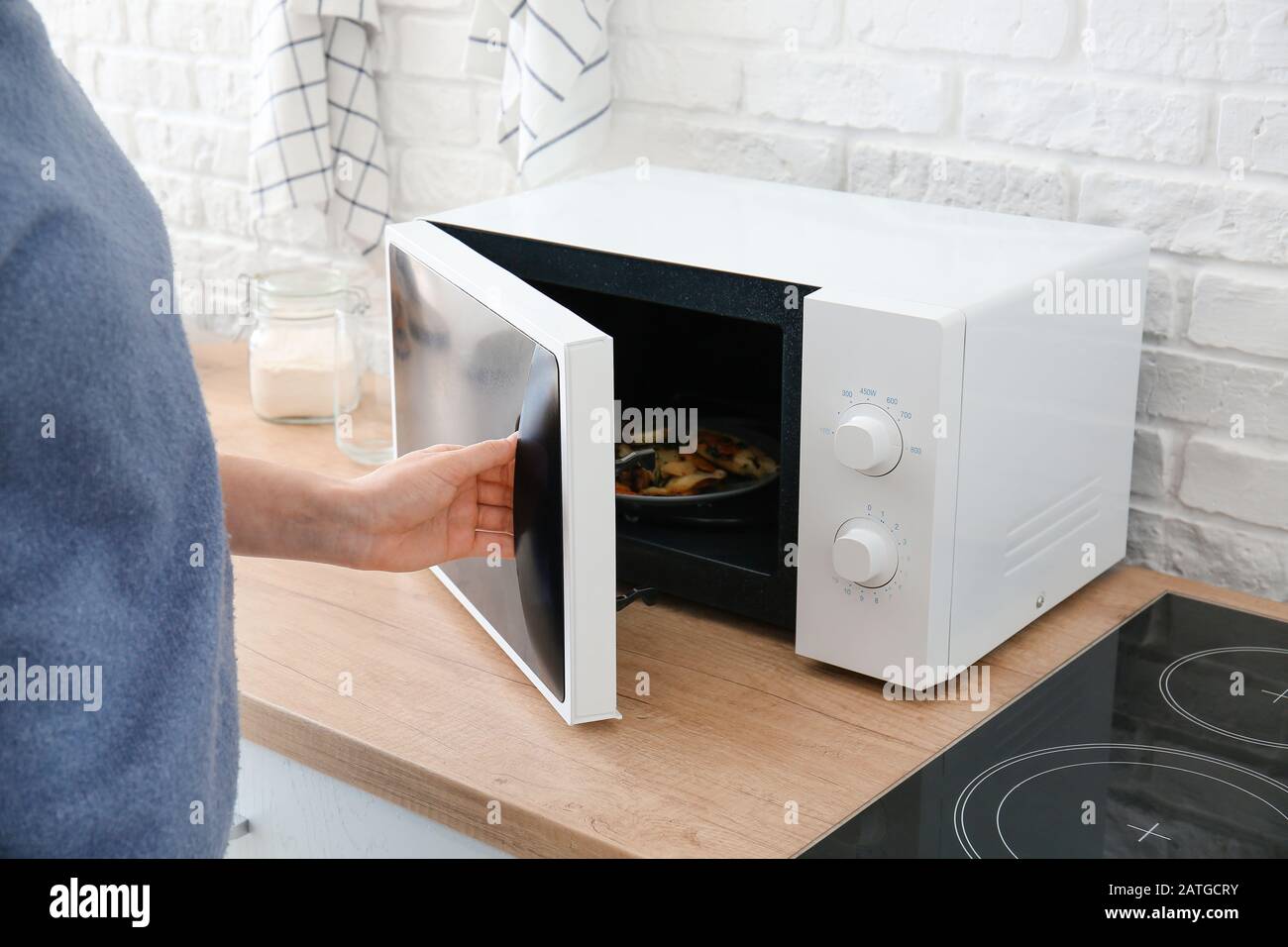 Woman opening modern microwave oven in kitchen Stock Photo - Alamy