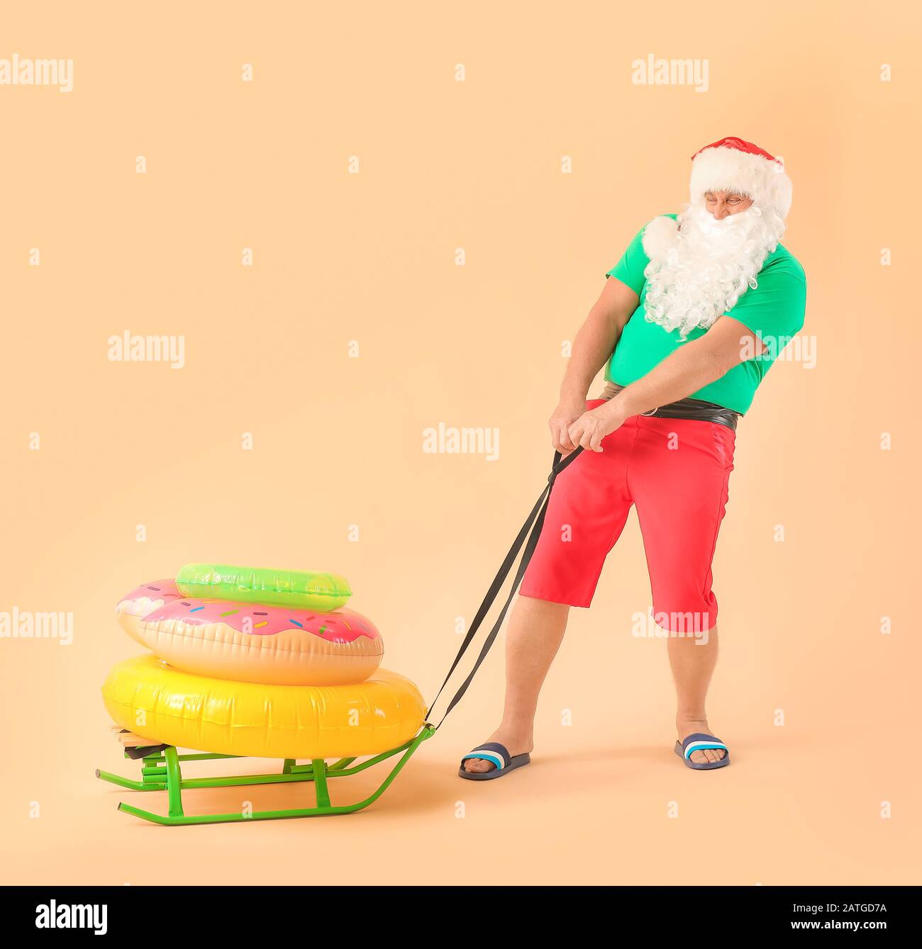 Santa Claus with swimming rings and sledges on color background ...