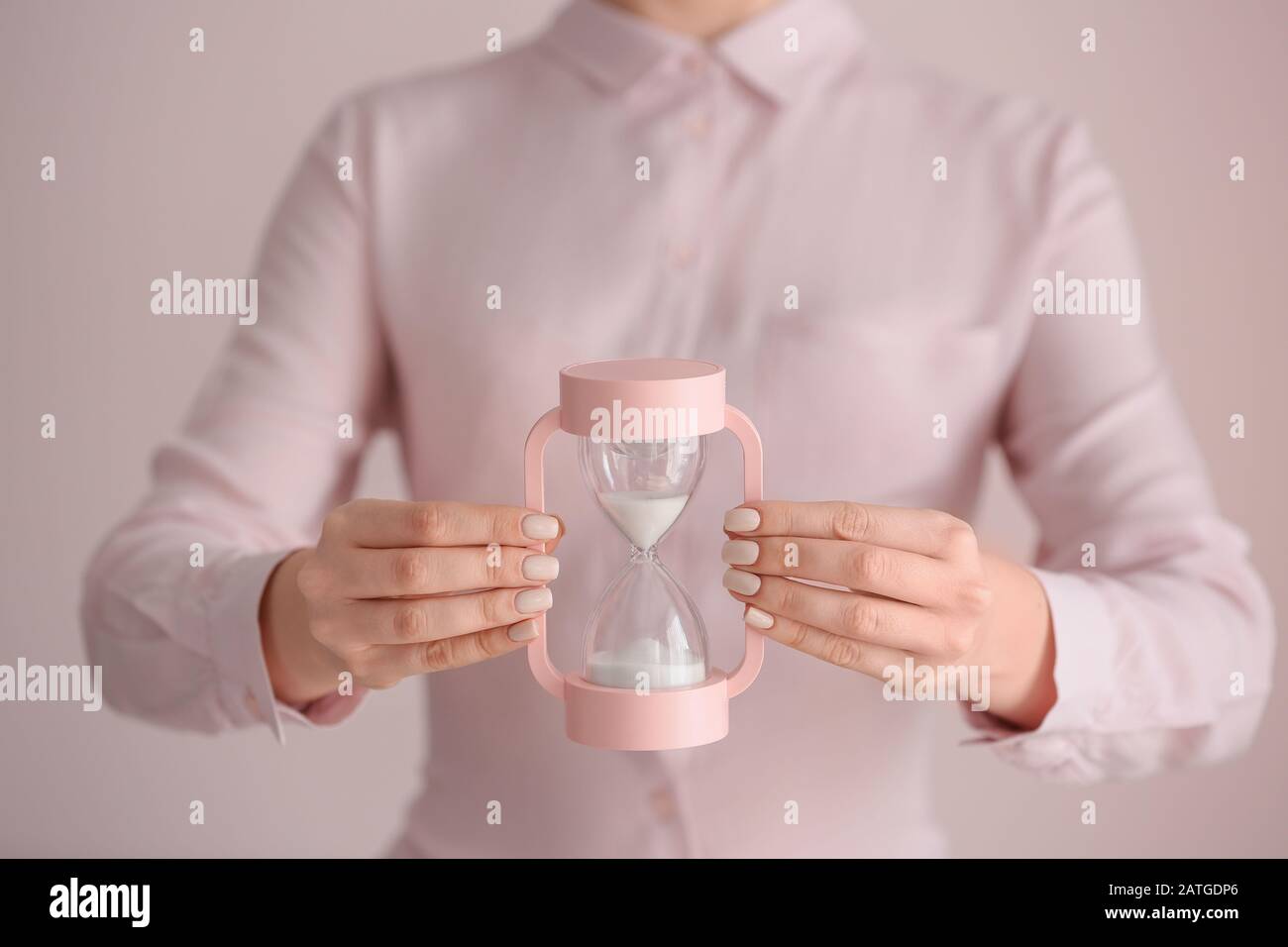 Woman with hourglass on light background, closeup. Time management ...