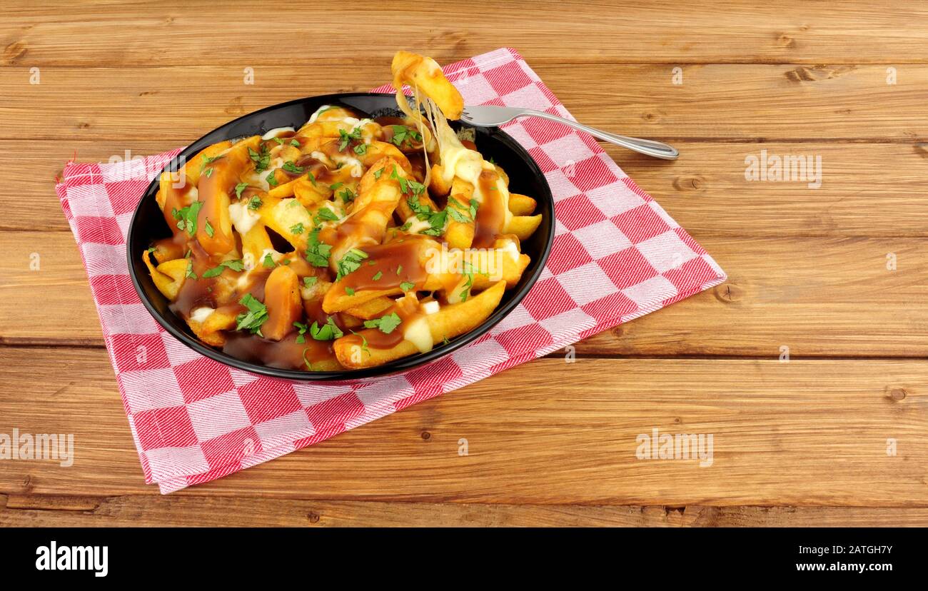 Bowl of traditional Canadian poutine on a wooden background Stock Photo ...
