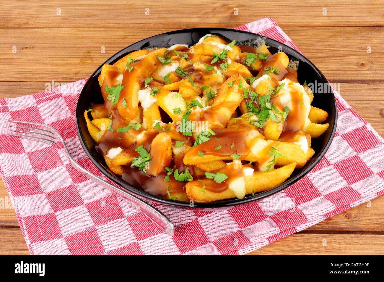 Bowl of traditional Canadian poutine on a wooden background Stock Photo ...
