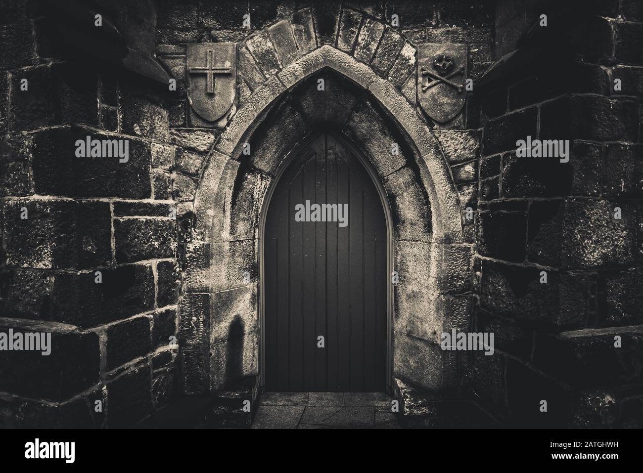 Scary pointy wooden door in an old and wet stone wall building with ...