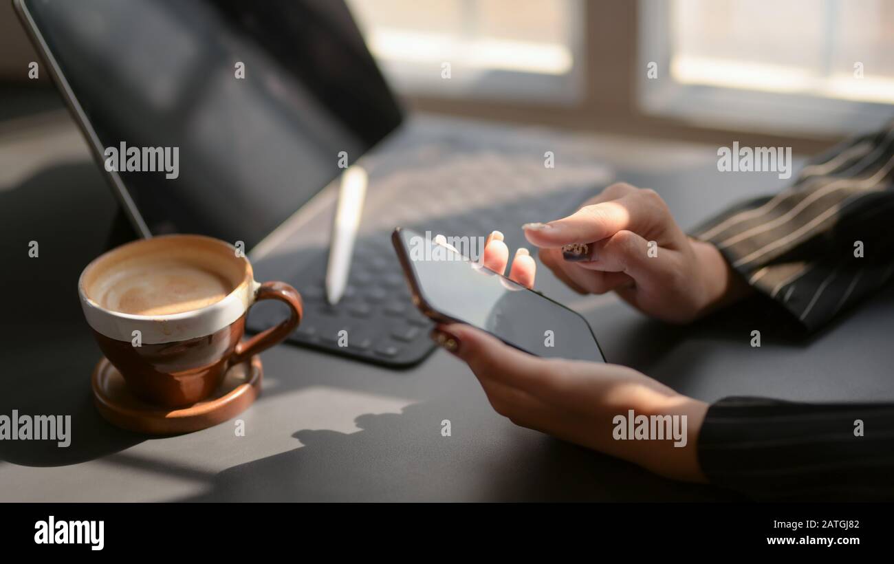 Side view of female using mock up smartphone with digital tablet and ...