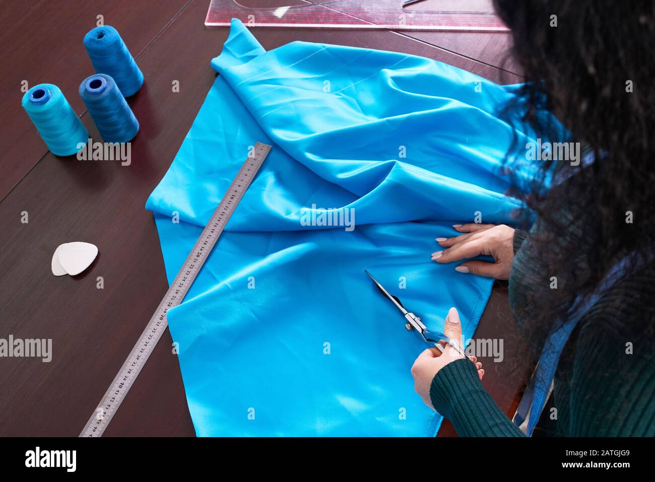 Dressmaker cutting fabric in atelier shop Stock Photo - Alamy