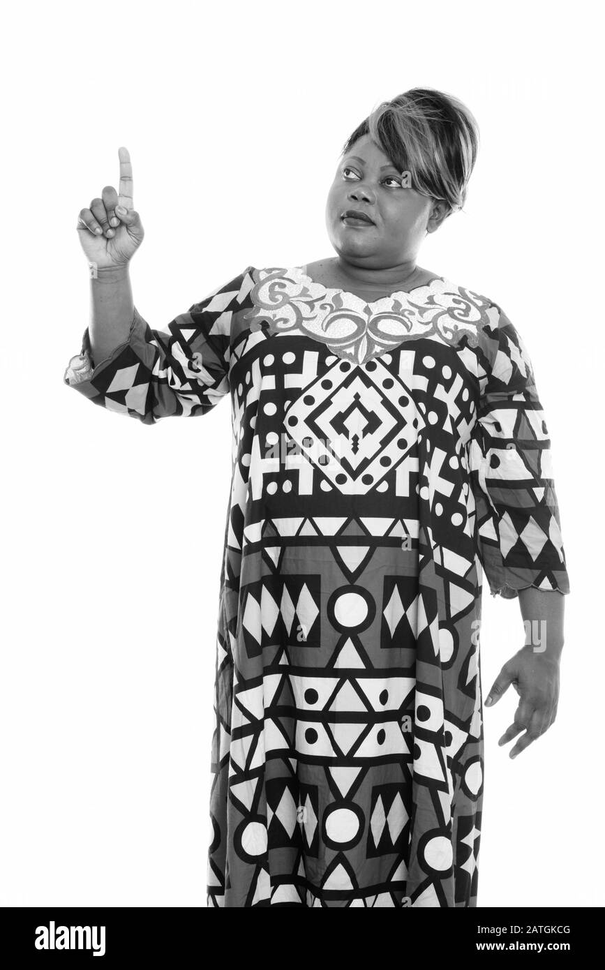 Studio shot of overweight African woman thinking and standing while ...