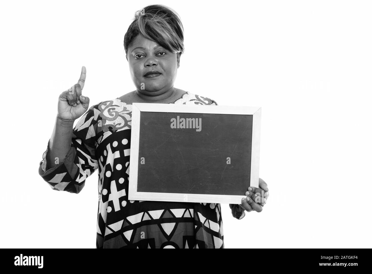 Portrait of beautiful overweight African woman pointing up while ...