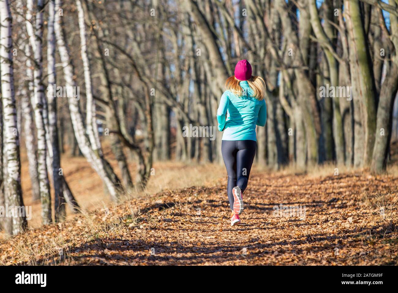 Back view of running girl in fall park in the morning. Sporty jogging ...
