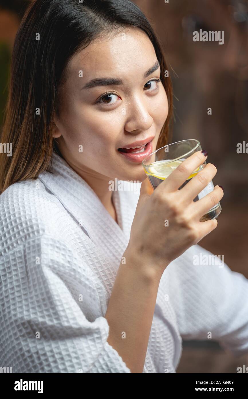 Cute charming Asian lady drinking tea after beauty procedures in salon ...