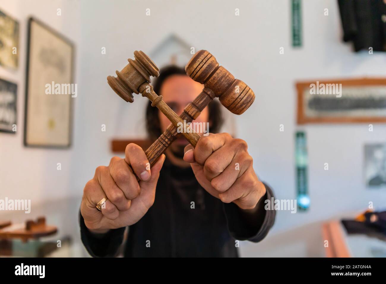 Young man holding two wooden hammers crossed showing as a symbol of no ...