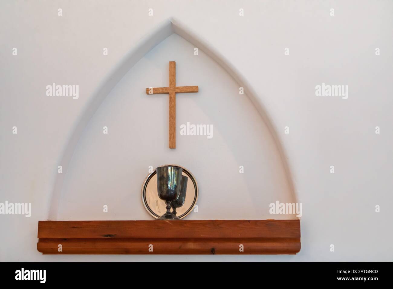 A wooden cross on church wall. Religious cross on interior wall of ...