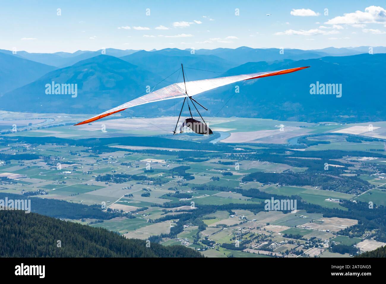 Hang glider soars above the hillside and town. Hang glider in action ...