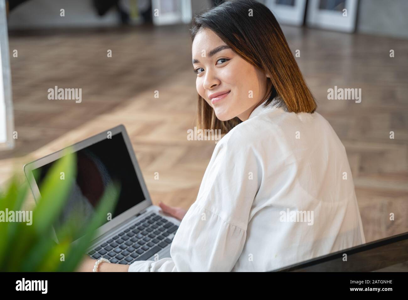 Happy Asian lady posing for camera on sofa Stock Photo - Alamy