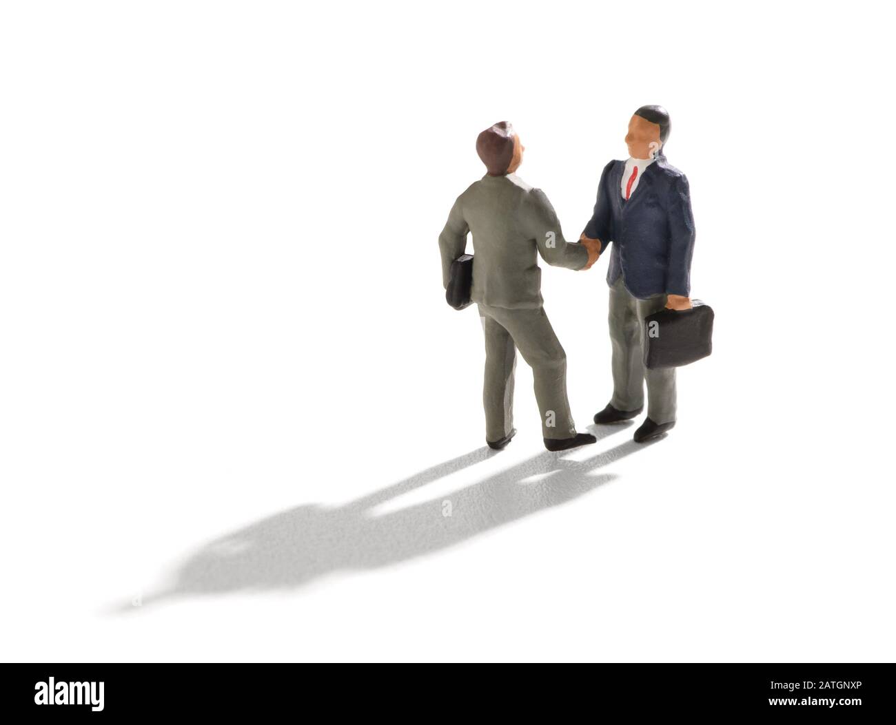Miniature businessmen shaking hands, isolated on white background with ...