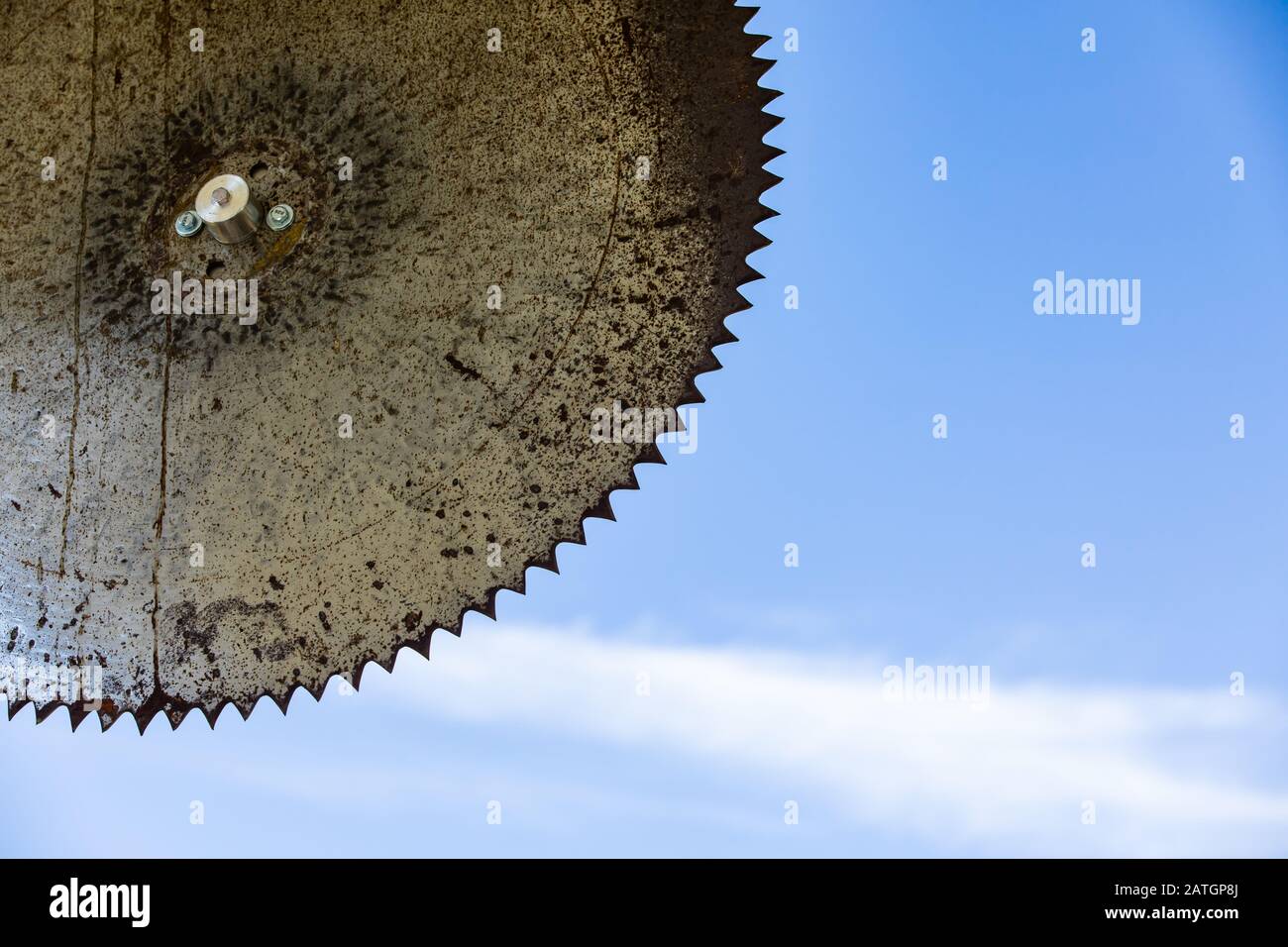 An old rustic saw wheel hanging against the clear sky. Extreme close-up ...
