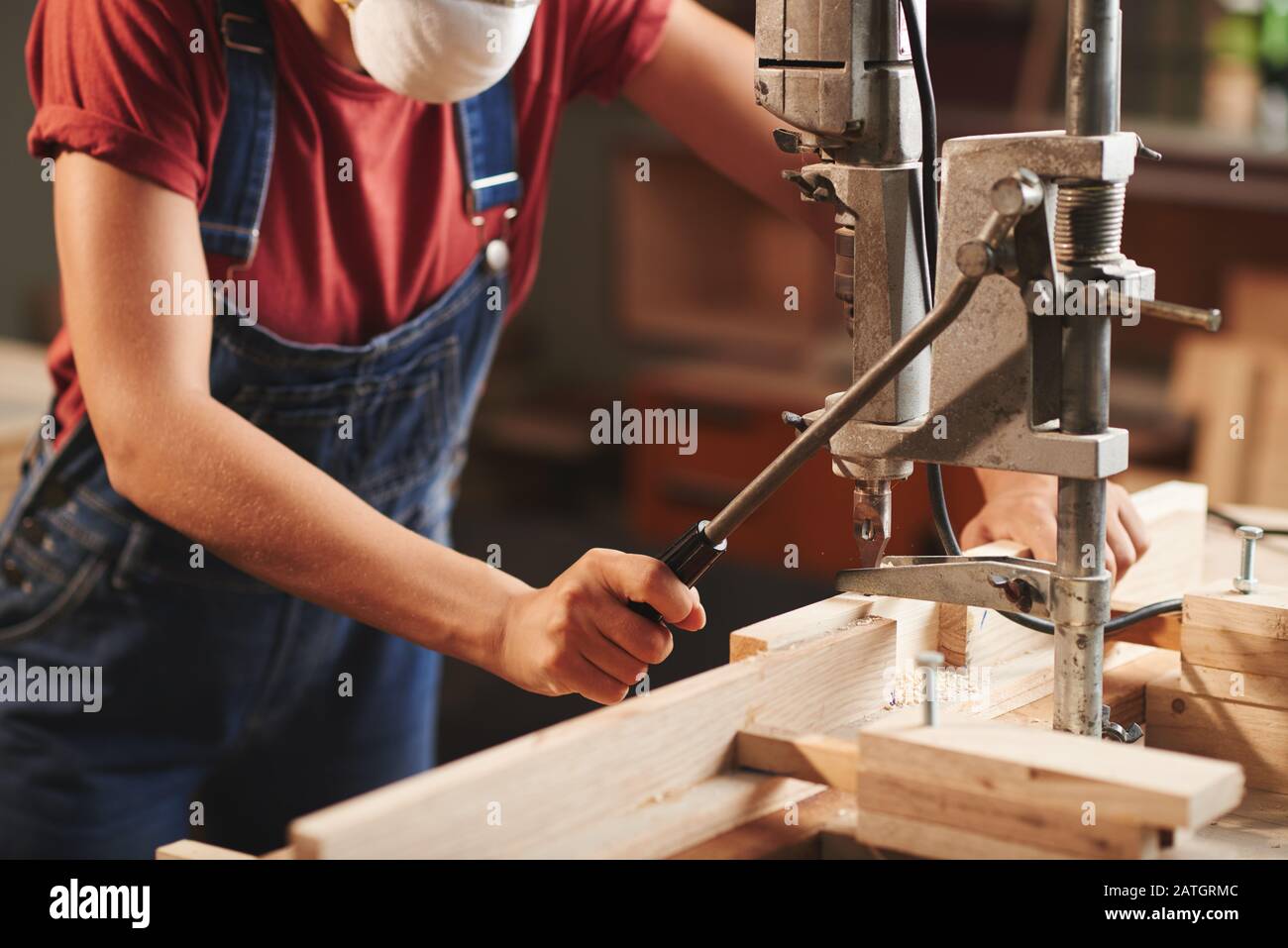 Close-up view of female carpenter in denim overall pressing lever on ...