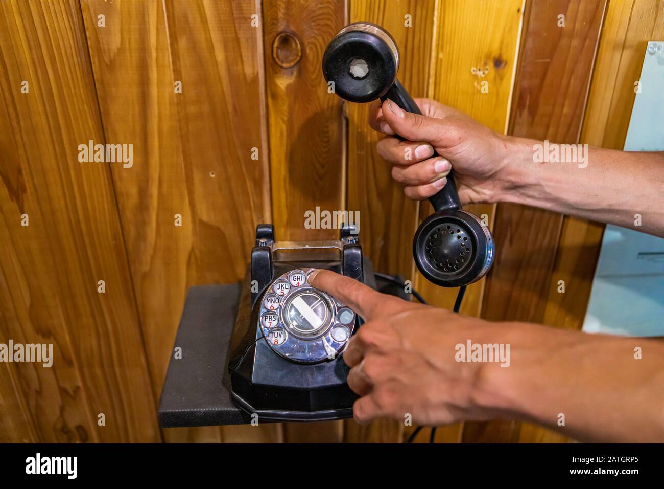 Unrecognizable man trying to call with an old phone. Making a phone ...