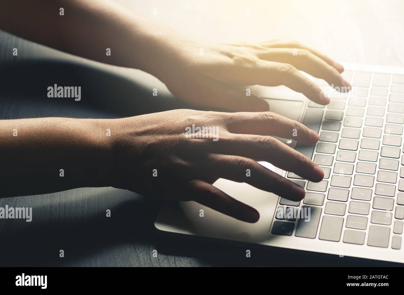 man hand using laptop on black desk with blur background and light ...