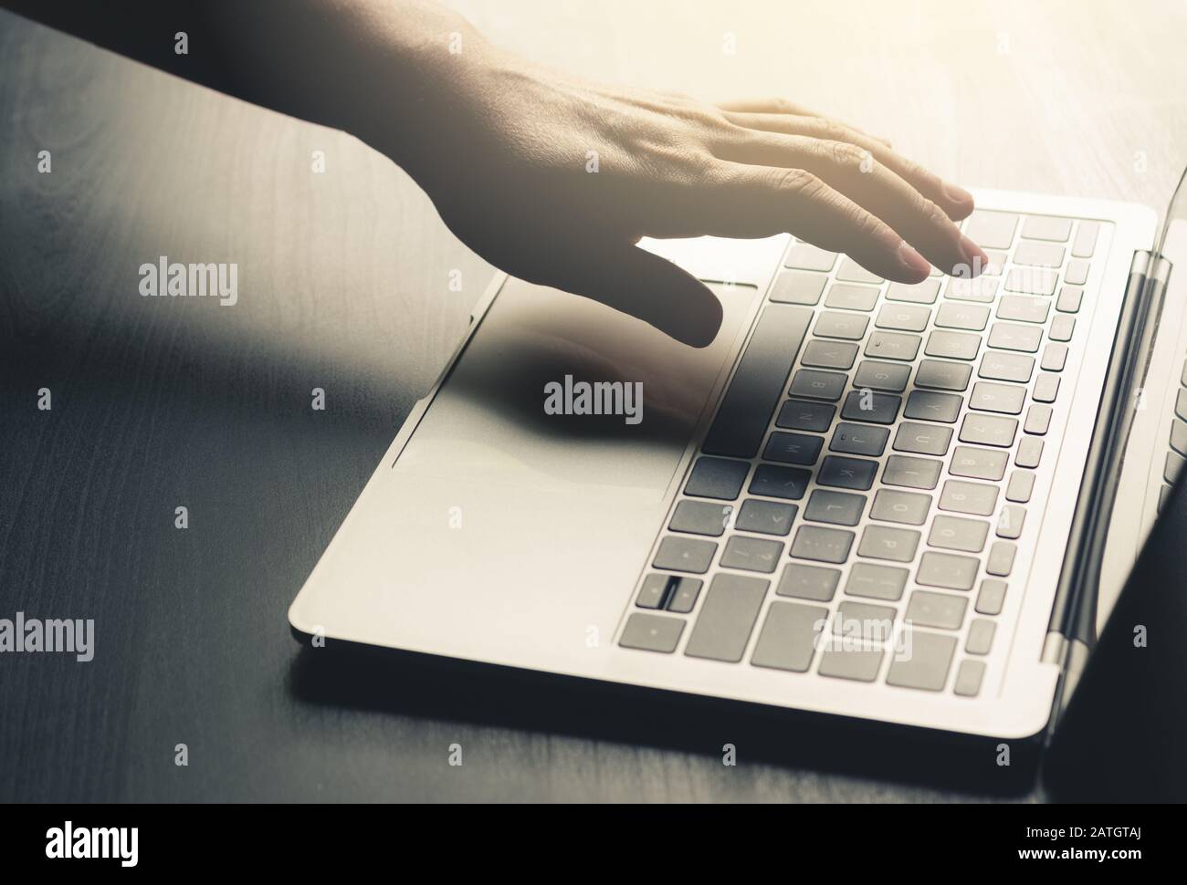man hand using laptop on black desk with blur background and light ...