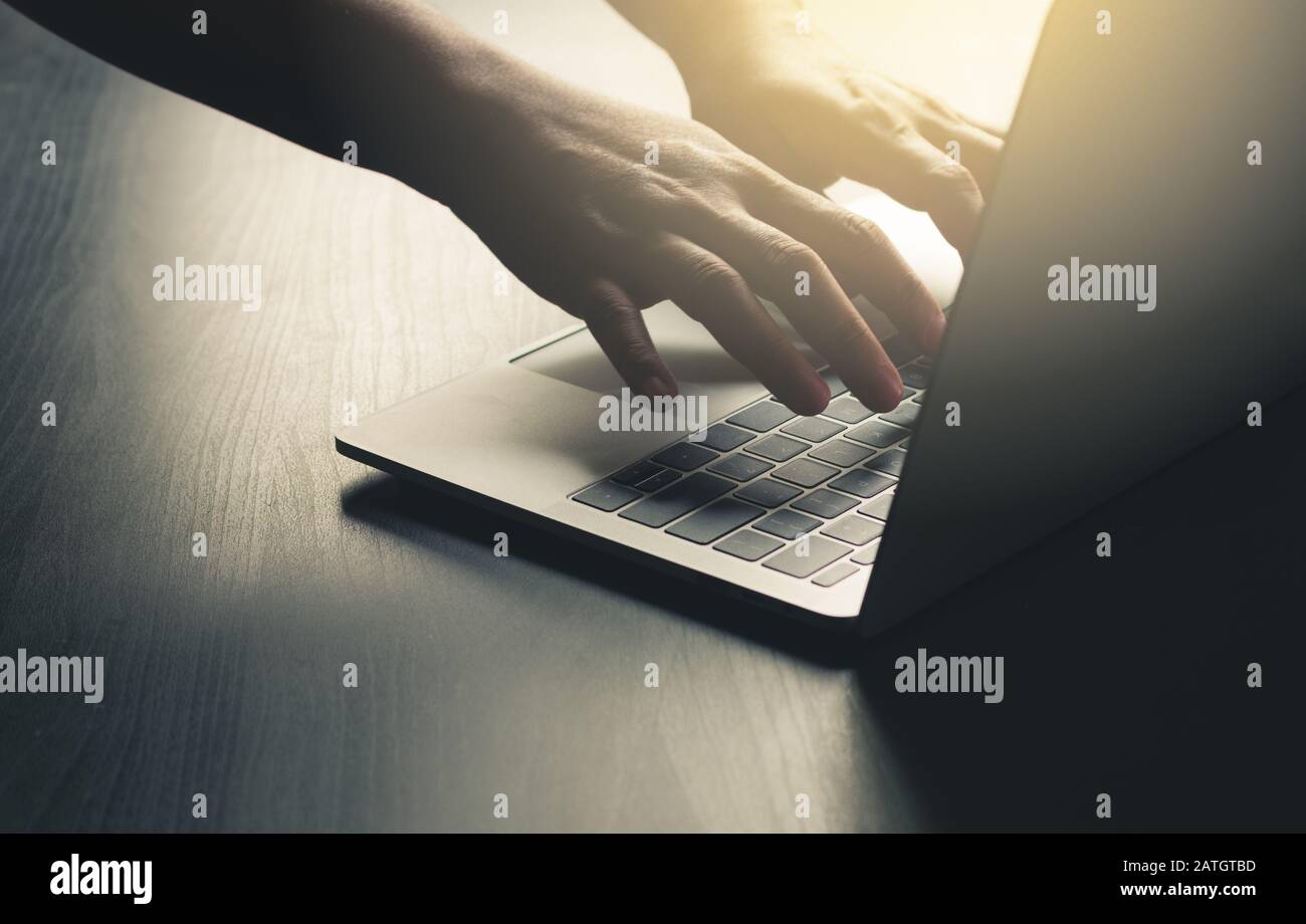 man hand using laptop on black desk with blur background and light ...