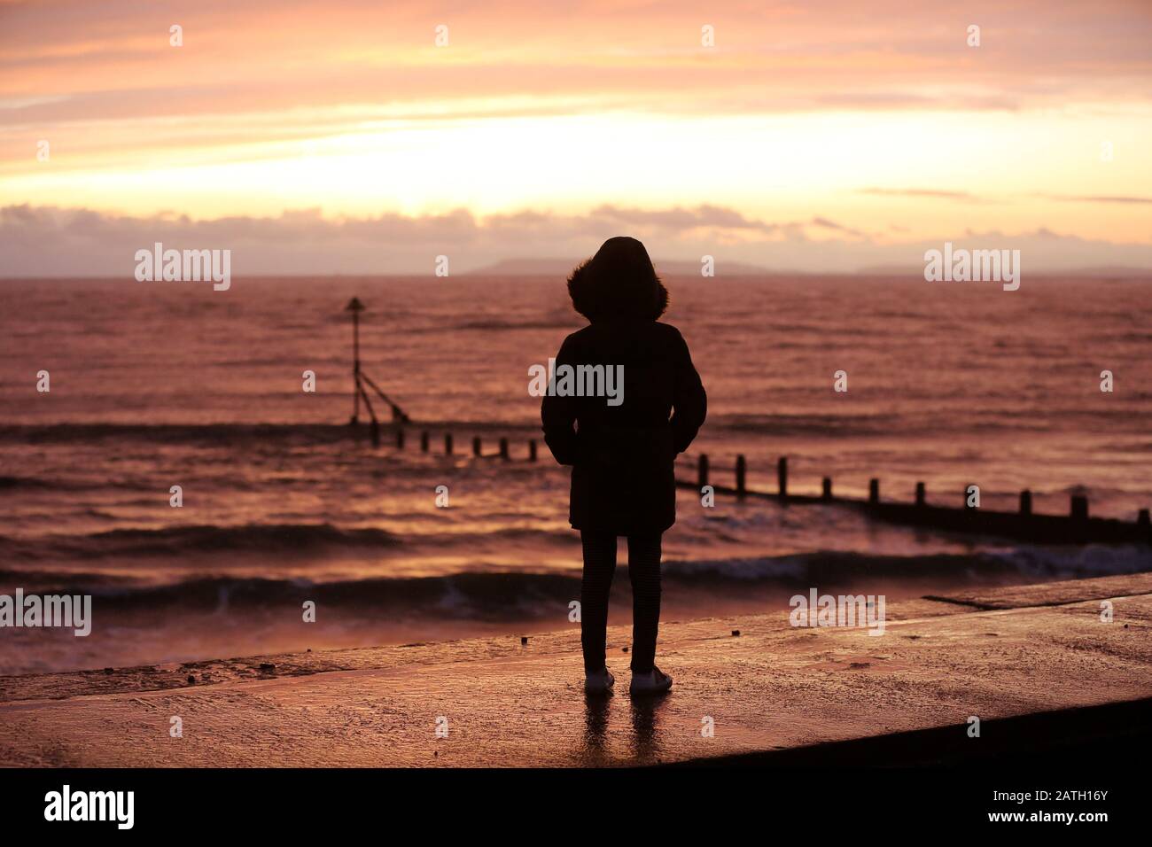 A kid looking out over a sunset in Selsey, West Sussex, UK Stock Photo ...