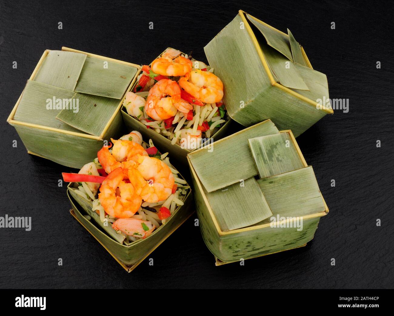 Steamed prawns and rice in bamboo leaf boxes on a slate stone ...