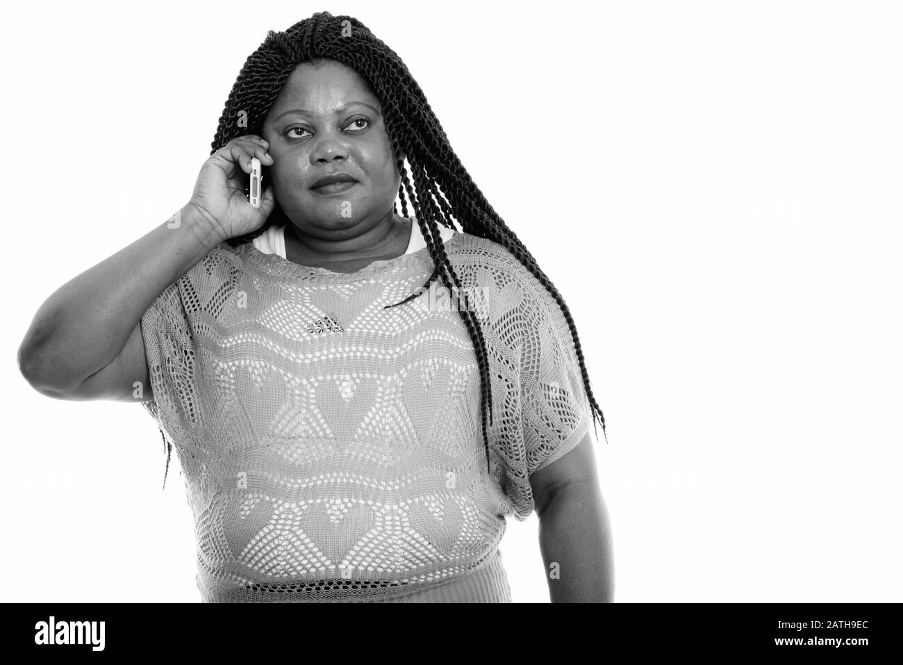 Studio shot of fat black African woman thinking while talking on mobile ...