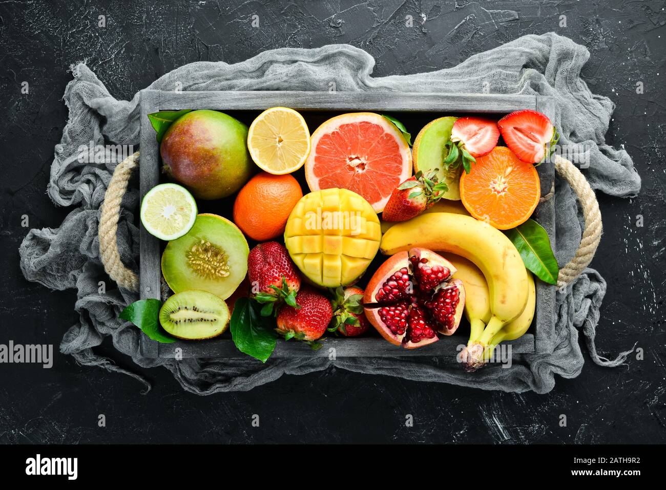 Fruits in a wooden box. Citrus, melon, pomegranate, strawberry, banana ...