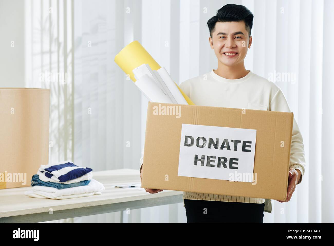 Portrait of happy excited handsome young Asian man with donation box ...