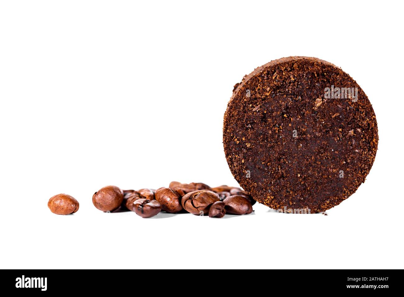 Coffee beans and round pressed coffee grounds in front of white ...