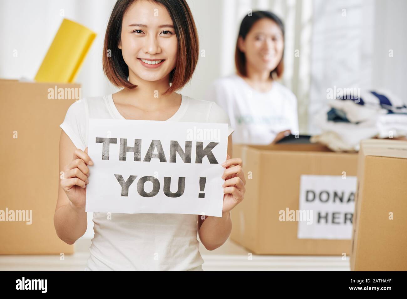 Lovely pretty young Asian woman with thank you placard in hands working ...