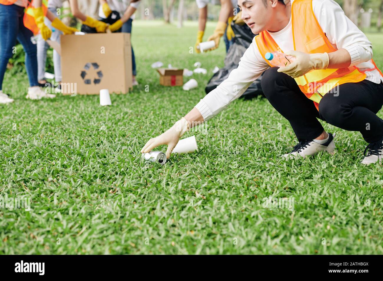 Cropped image of young Vietnamese volunteer picking up plastic bottles ...