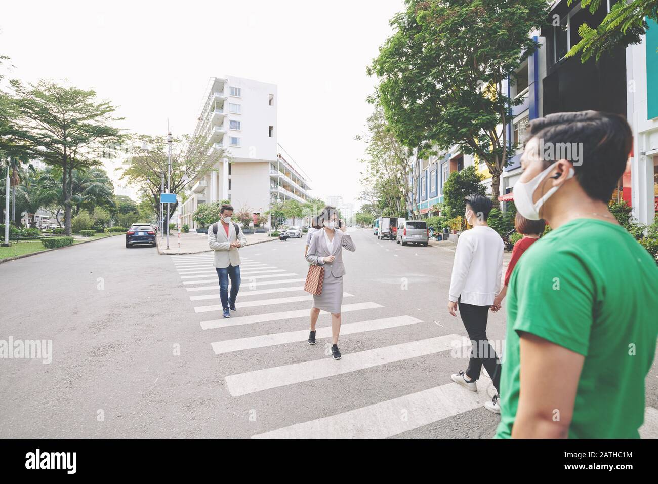 Asian people in protective maskes crossing road in quarantined city ...