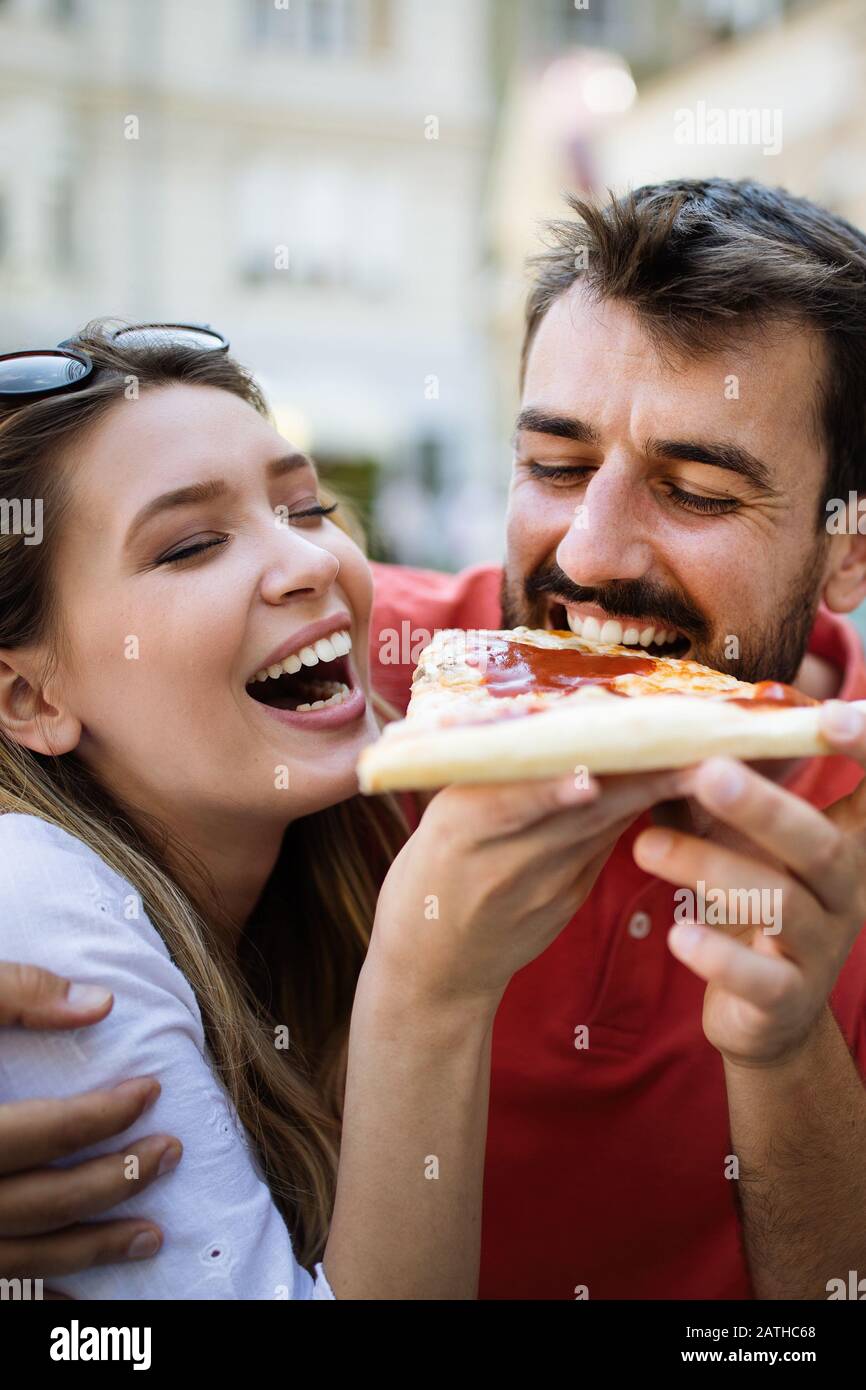 Happy couple laughing and eating pizza, having fun together Stock Photo ...