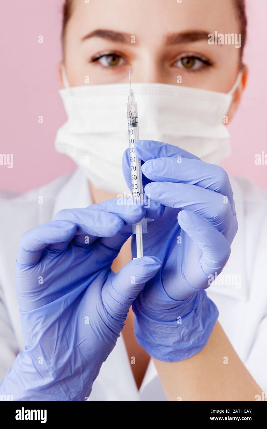 Close up nurse holding a syringe for injection, on pink background ...