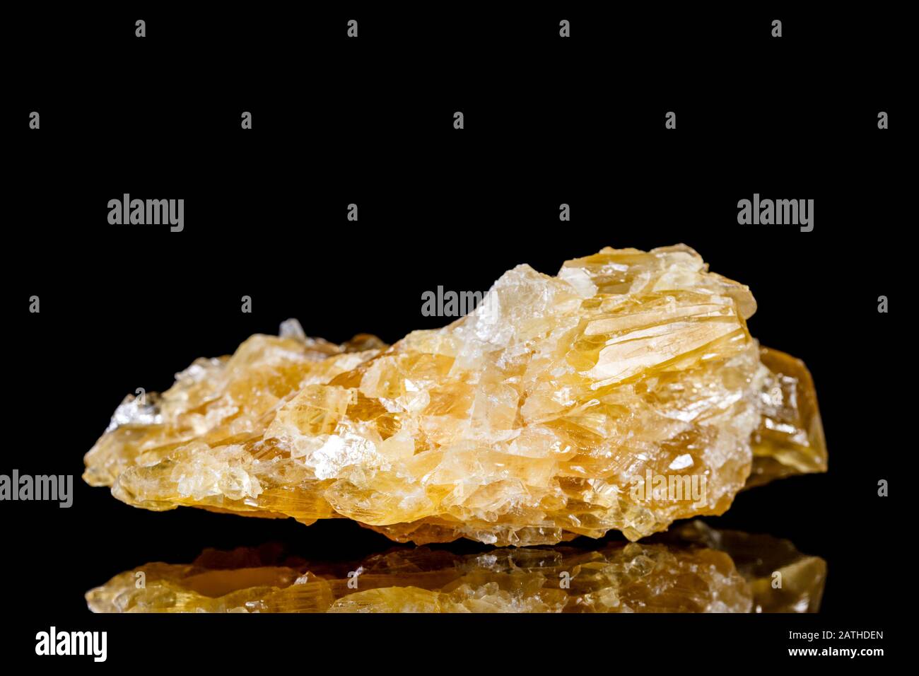 Raw honey calcite mineral stone in front of black background ...