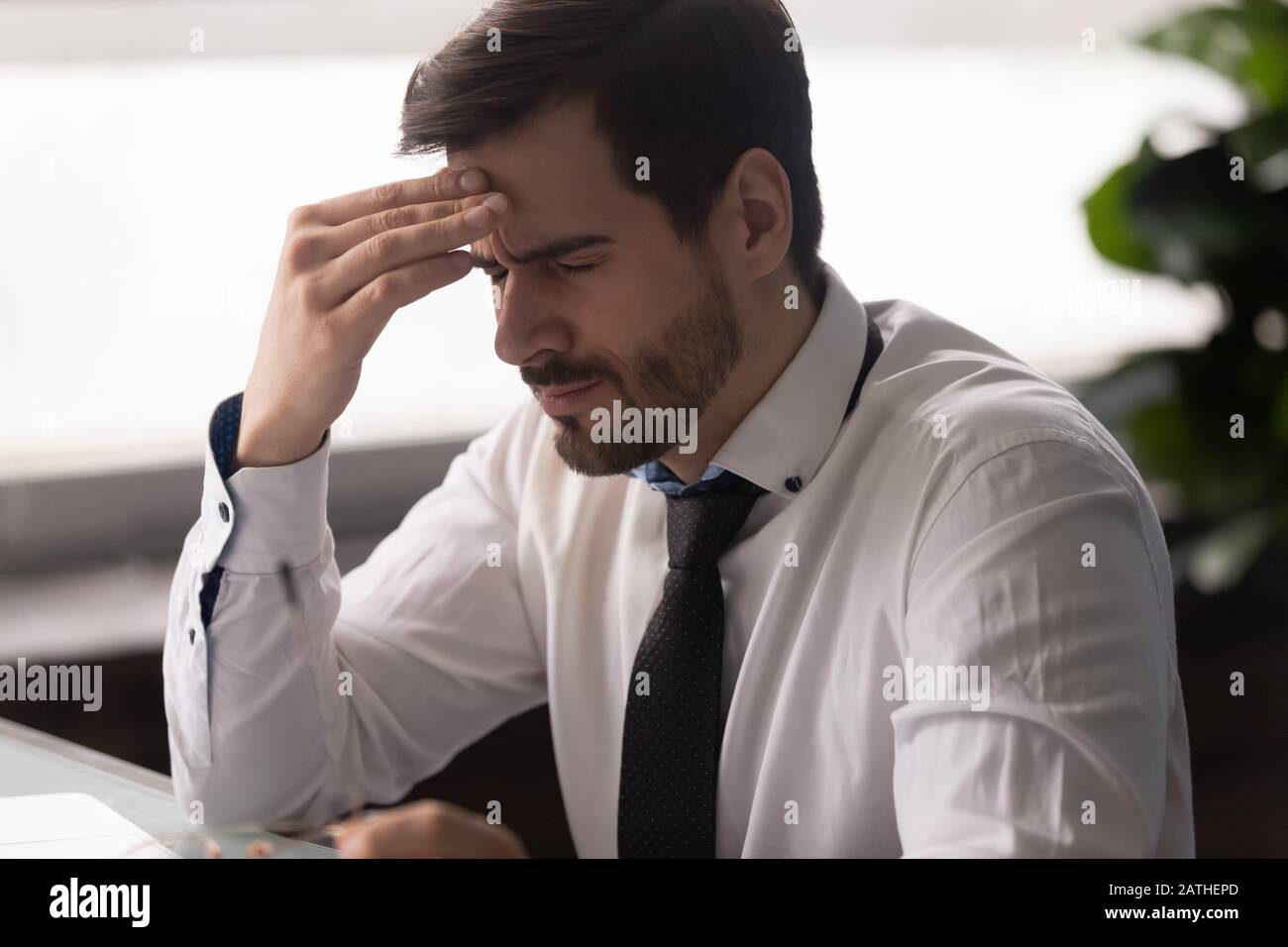 Businessman suffering from headache at workplace feeling tired and ...
