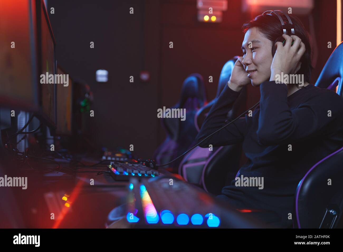 Side view portrait of smiling Asian man putting on headphones ready to ...