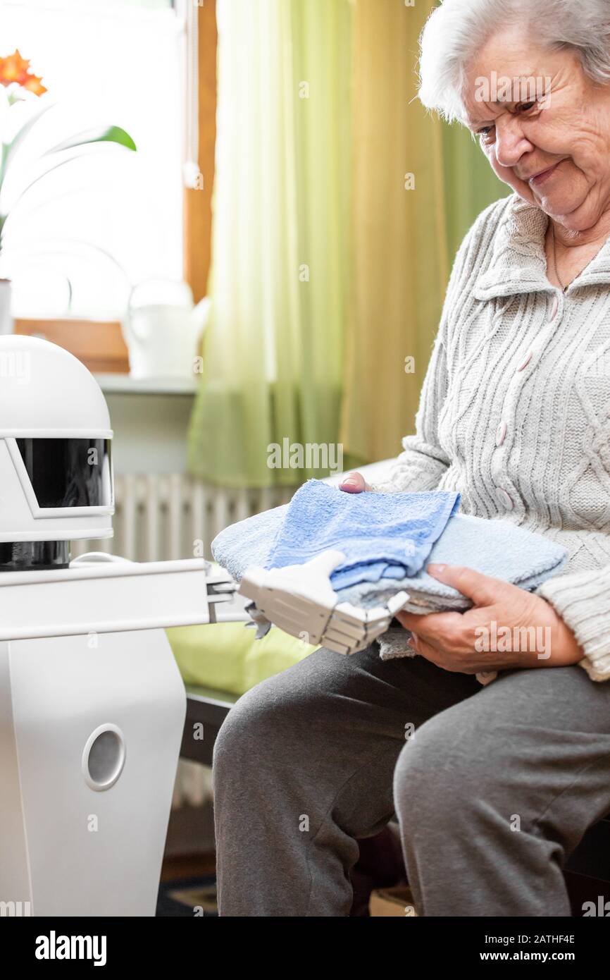 autonomous caregiver robot is holding two towels, giving them to an ...