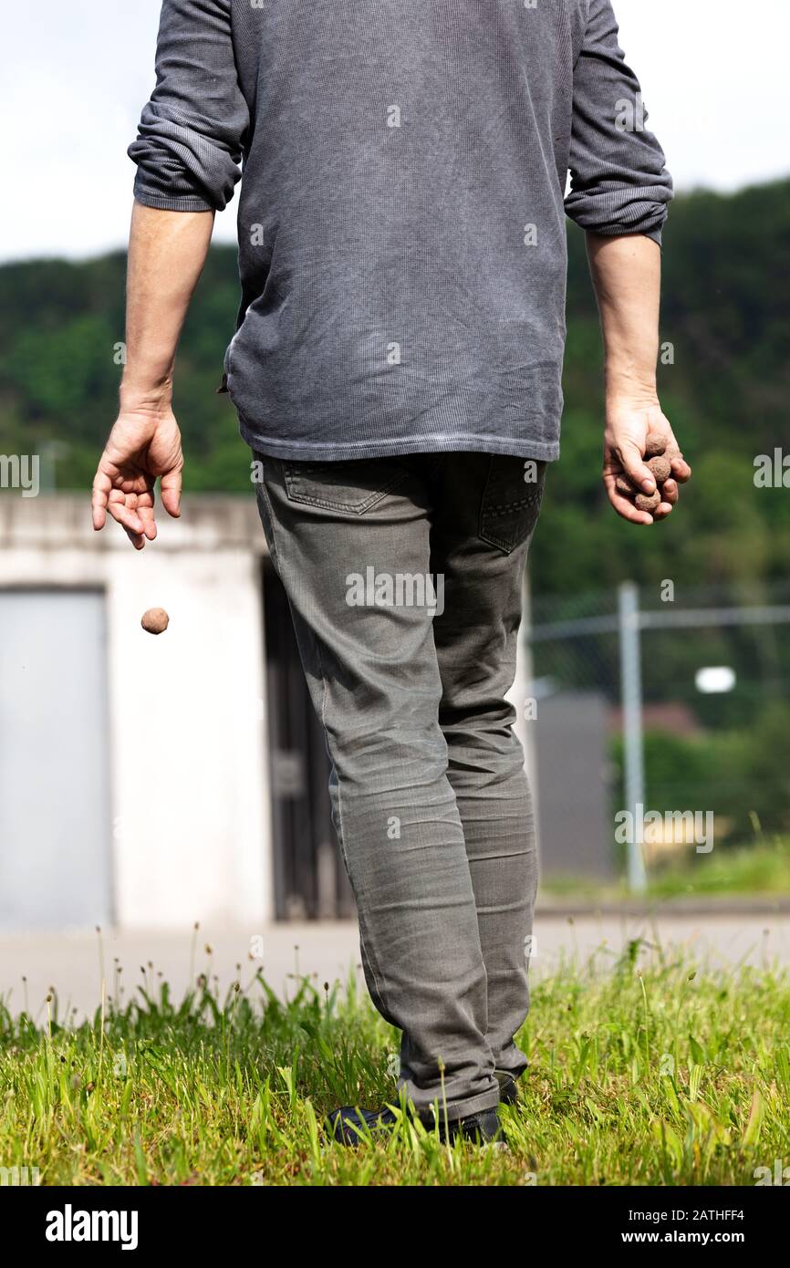 man is holding and throwing seed balls or seed bombs in front of a ugly ...