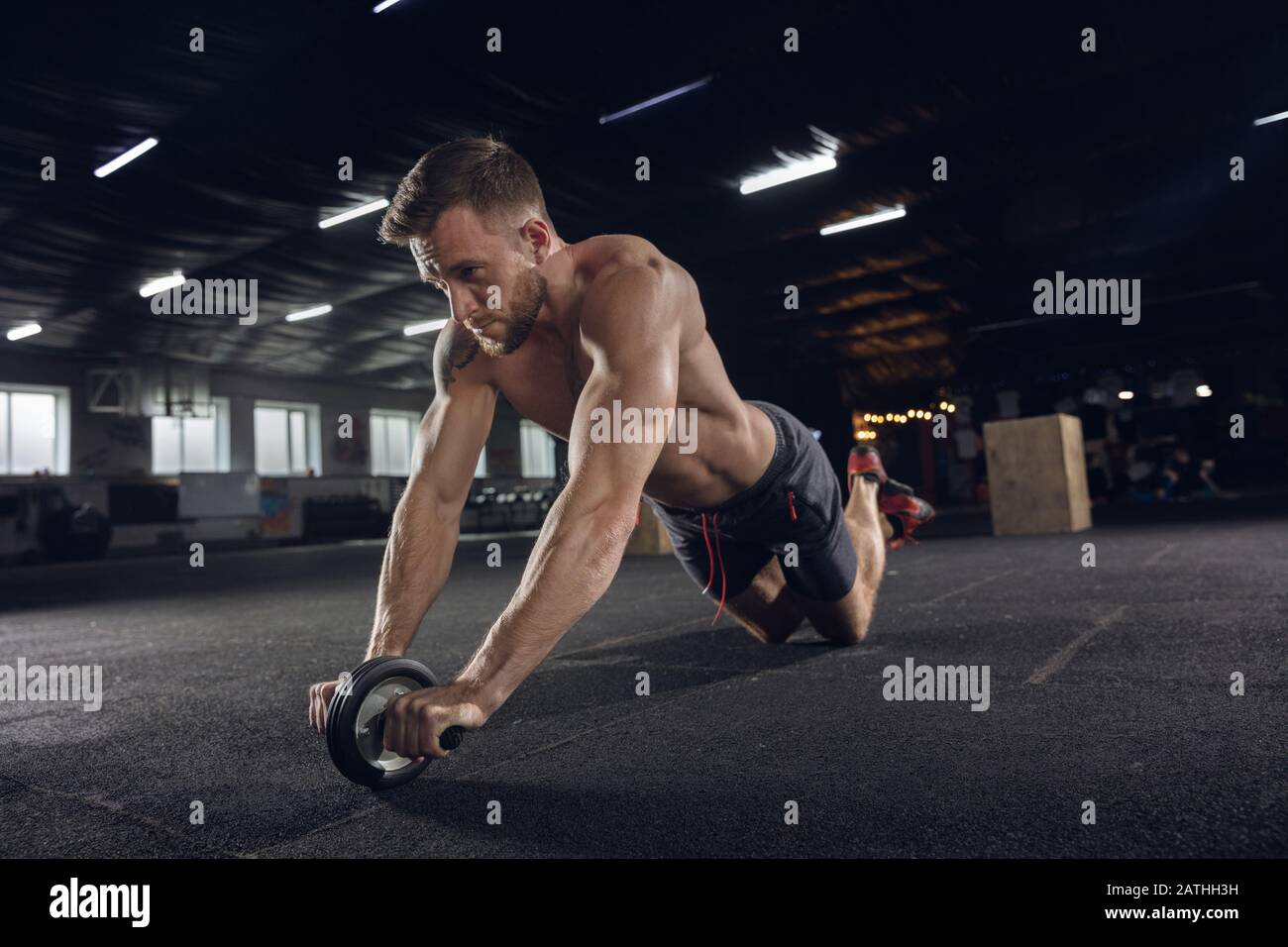 Young healthy man, athlete doing exercises with the roller in gym ...