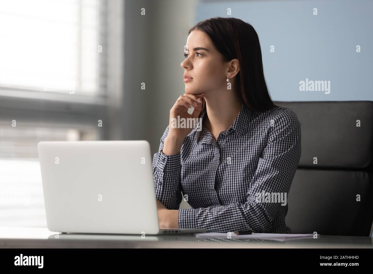 Pensive female employee sitting at desk distracted from work Stock ...