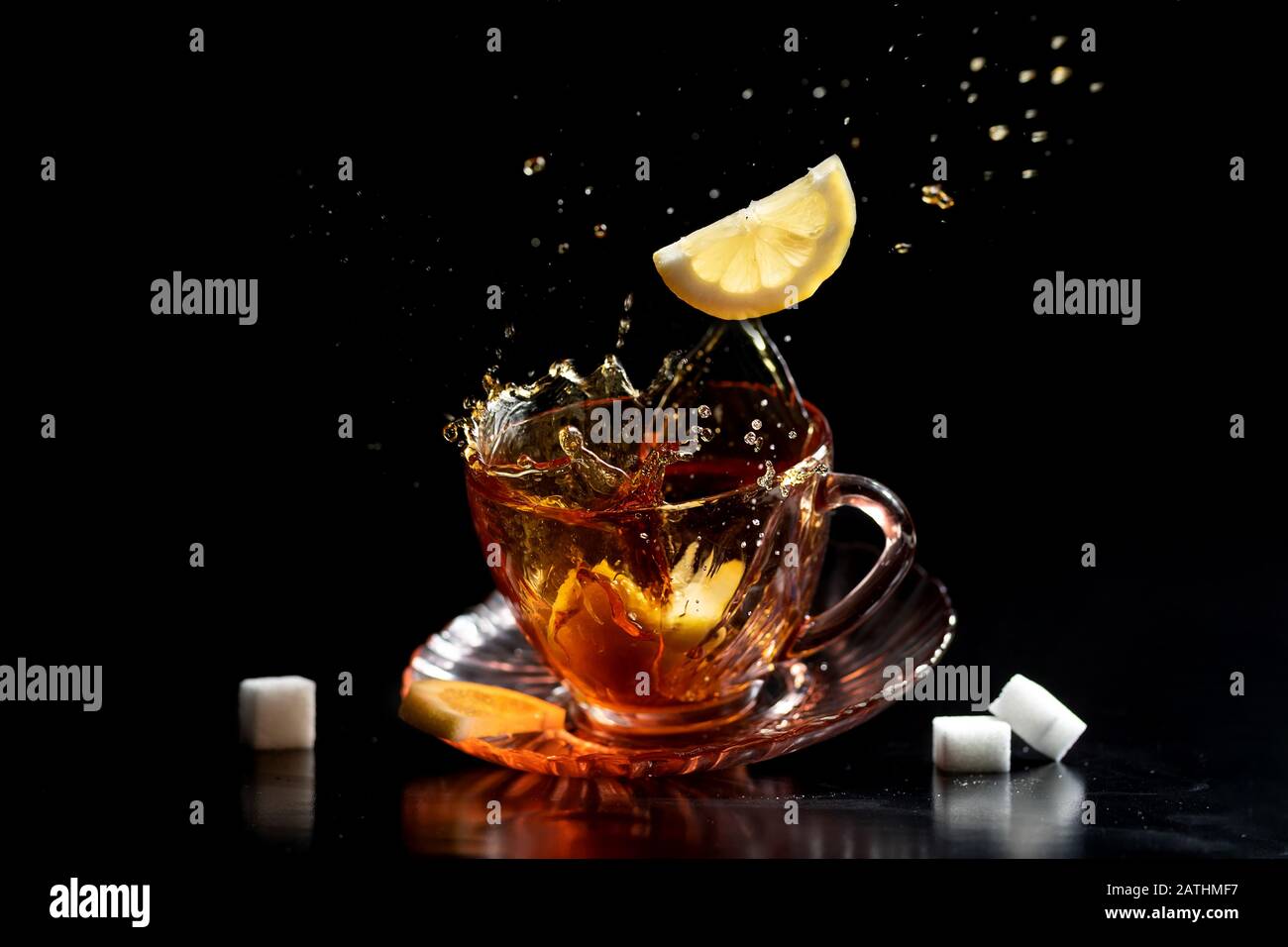 Lemon flies out of a tea mug on a black background with lots of ...