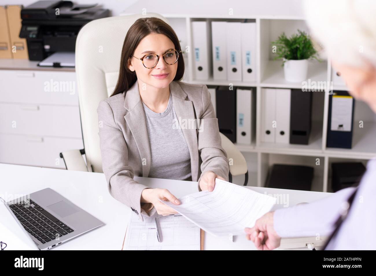 Over shoulder view of senior woman giving filled papers to bank ...