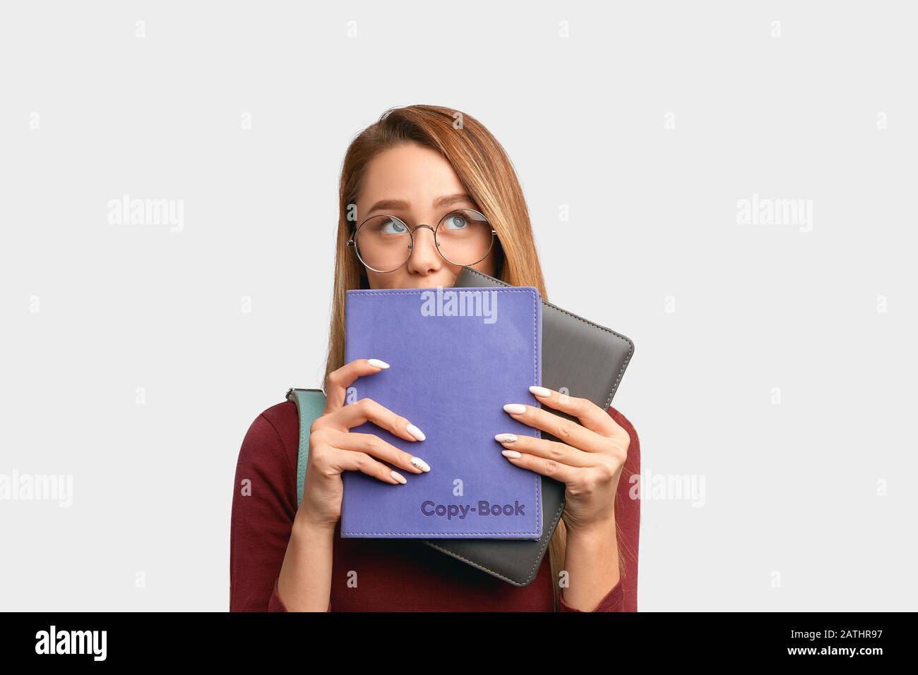 Student looks up, hiding behind books in Studio Stock Photo - Alamy