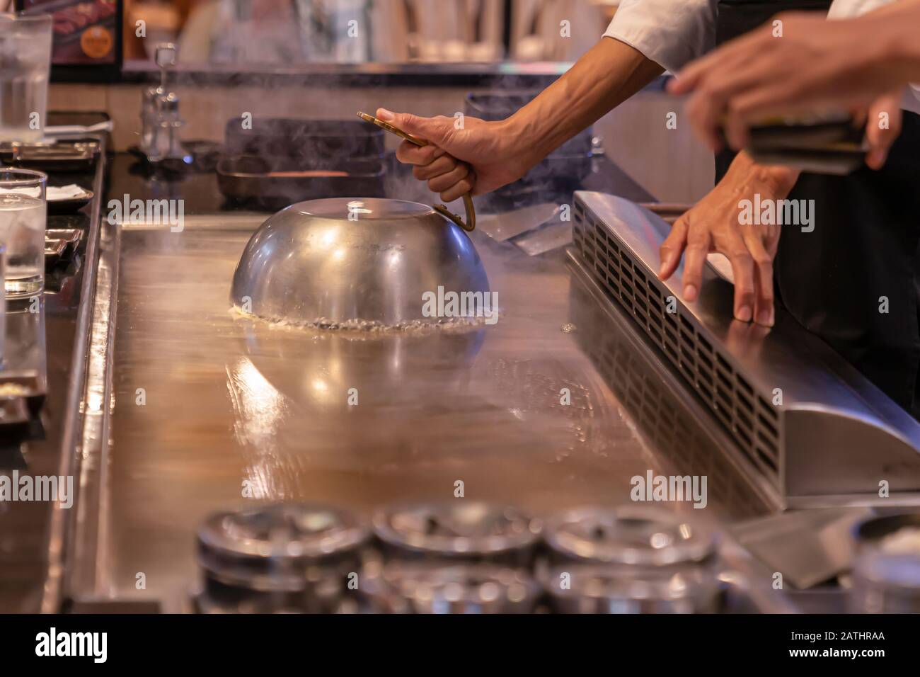 Teppanyaki, Japanese cuisine. cooking a dish covered with a lid on a ...