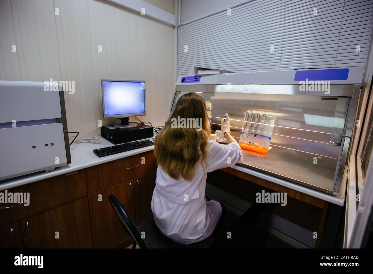 Scientist work in laminar box. She puts samples of DNA fragments for ...