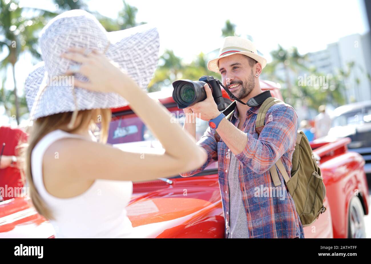 Photographer taking picture of model sitting in old fashioned pick-up ...